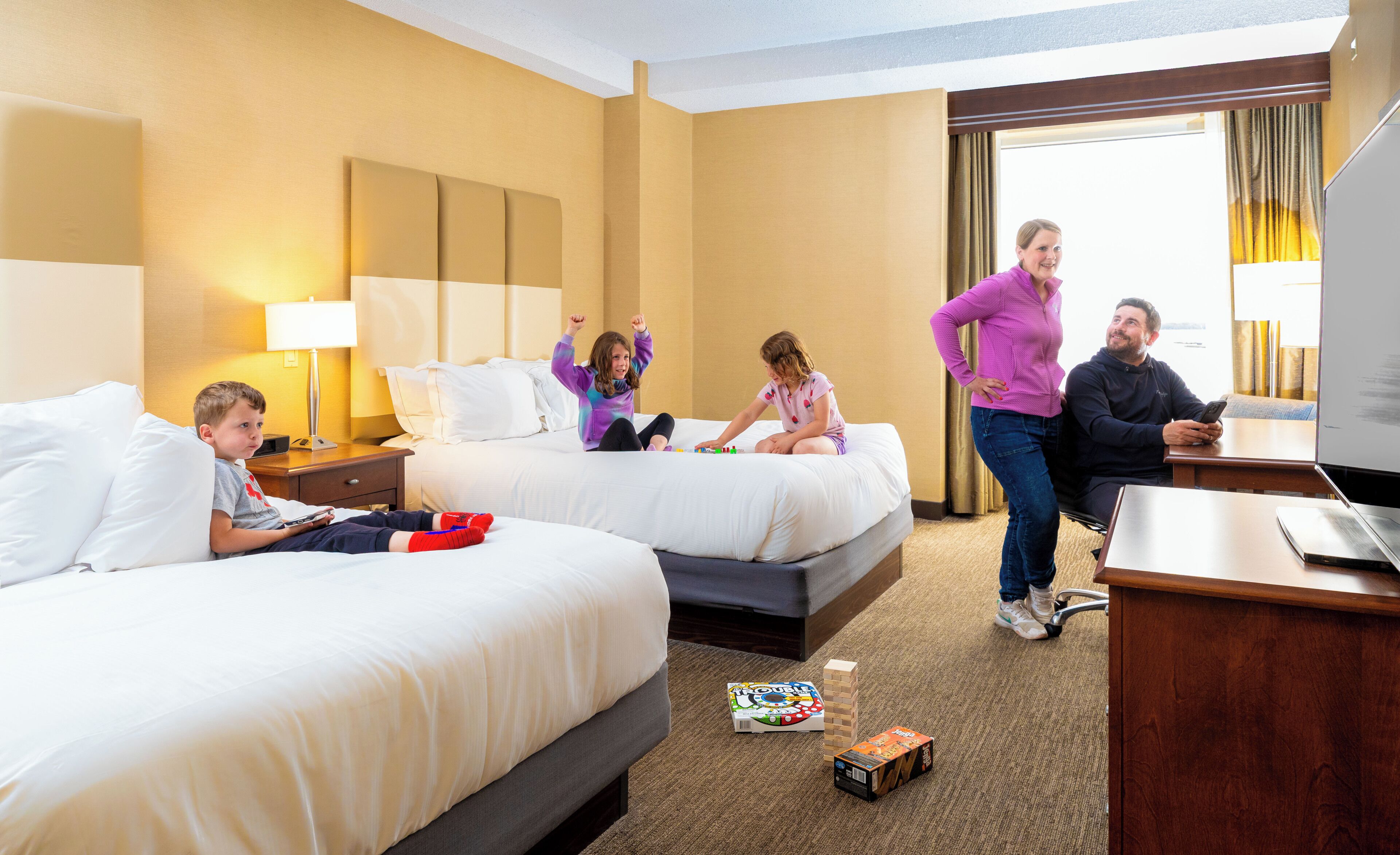Quarto de hotel com duas camas, uma escrivaninha e uma janela.