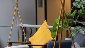 Uma sala de estar moderna com um sofá, um travesseiro amarelo e um abajur.