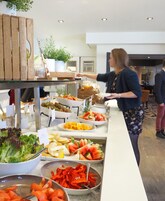 Uma área de buffet com diversas opções de comida, incluindo frutas, legumes e saladas.
