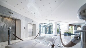 Um lobby moderno com uma receção em mármore, uma área de espera com paredes de vidro e um design limpo e minimalista.