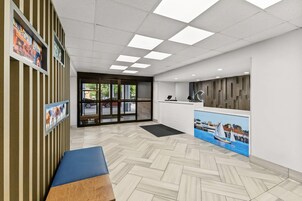 Uma área de recepção com balcão de check-in, um banco e vista para o exterior.