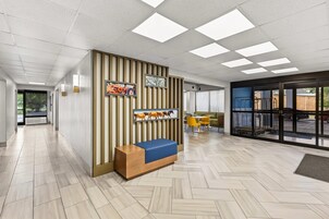 Um interior moderno com uma mesa de recepção, um painel de exibição na parede e uma área de estar.