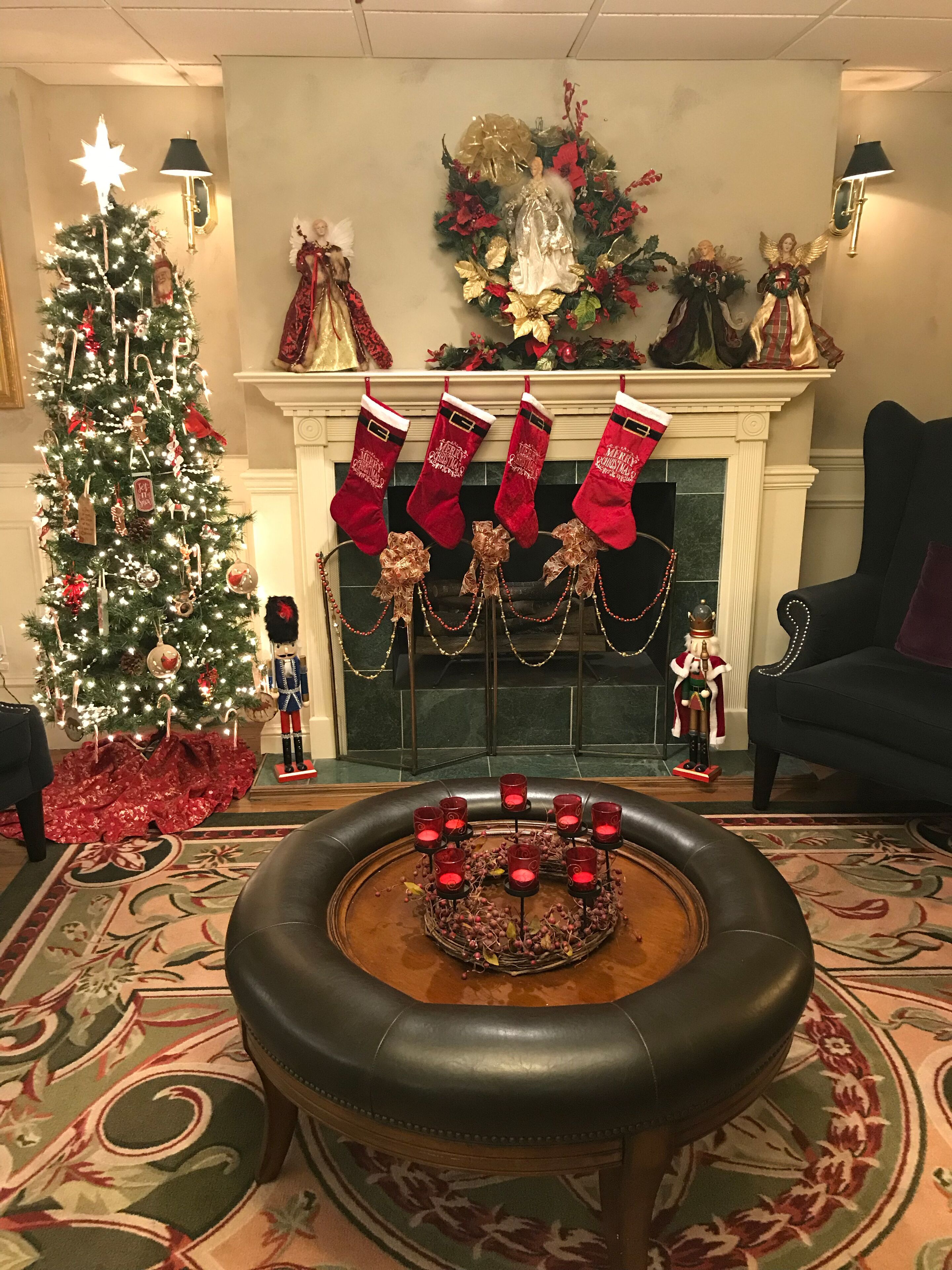 Uma sala de estar acolhedora com uma árvore de Natal, lareira, meias decorativas e uma mesa de centro.