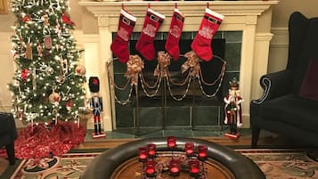 Uma sala de estar acolhedora com uma árvore de Natal, lareira, meias decorativas e uma mesa de centro.