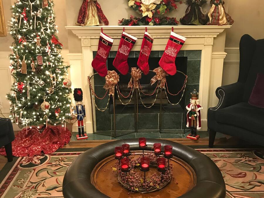 Uma sala de estar acolhedora com uma árvore de Natal, lareira, meias decorativas e uma mesa de centro.