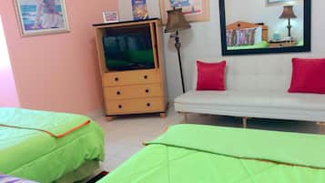 Quarto de hotel com duas camas, televisão, sofá e obras de arte nas paredes.