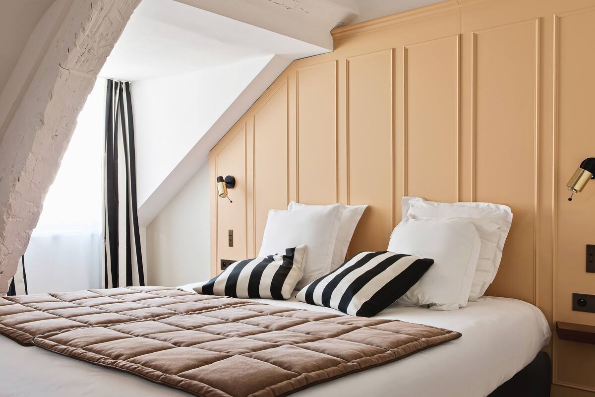 Um quarto com uma cama grande, almofadas listradas e uma cabeceira clara.