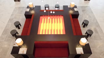 Um hall com piso aquecido central, áreas de estar e mesas com luminárias.