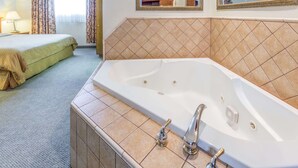 Um banheiro com uma banheira grande e branca, um banco de madeira e uma parede revestida de azulejos.