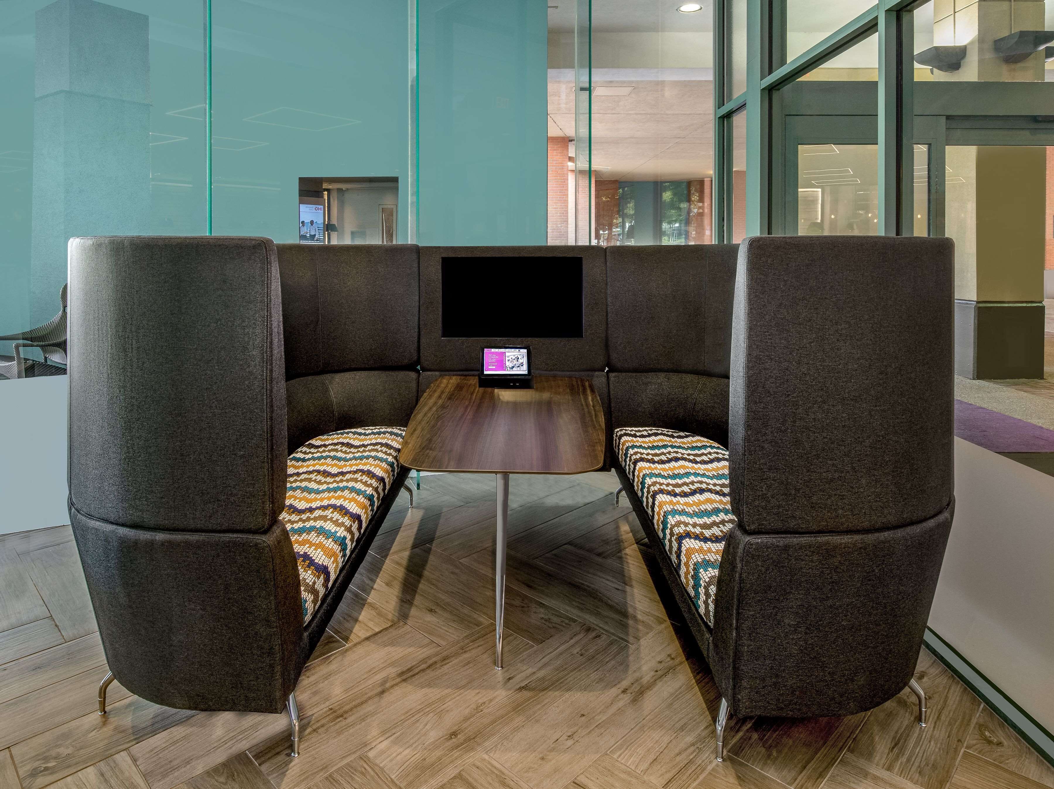 Um espaço de estar moderno e fechado, com televisão de tela plana, bancos acolchoados e uma mesa de madeira.