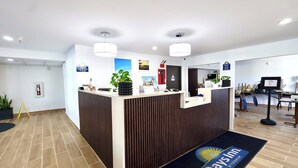 Uma receção com a placa Days Inn by Wyndham, um extintor de incêndio e uma planta no balcão.