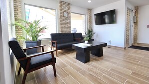 Uma área de estar moderna com sofá, cadeiras, mesa de centro e TV fixada na parede.