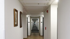 Um corredor comprido e estreito, com paredes brancas e soalho de madeira.