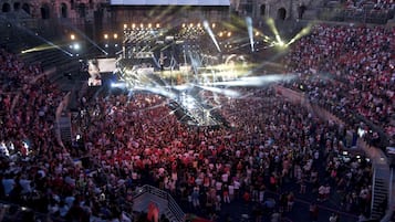 Espaço amplo e coberto com palco central e uma multidão ao redor.