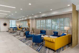 Uma sala de estar moderna com um sofá amarelo, poltronas azuis e um tapete estampado.