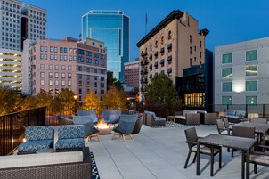 Um terraço ao ar livre com móveis de vime, lareira e vista para a cidade.