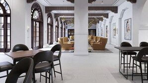 Um hall de hotel espaçoso com tetos altos, janelas amplas e mobiliário moderno.