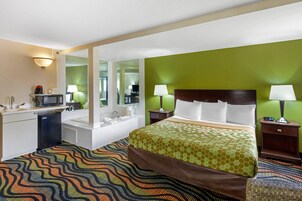 Quarto de hotel com cama, escrivaninha, banheiro e espelho.