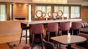 Um hall de hotel moderno com área de bar, assentos e lareira.