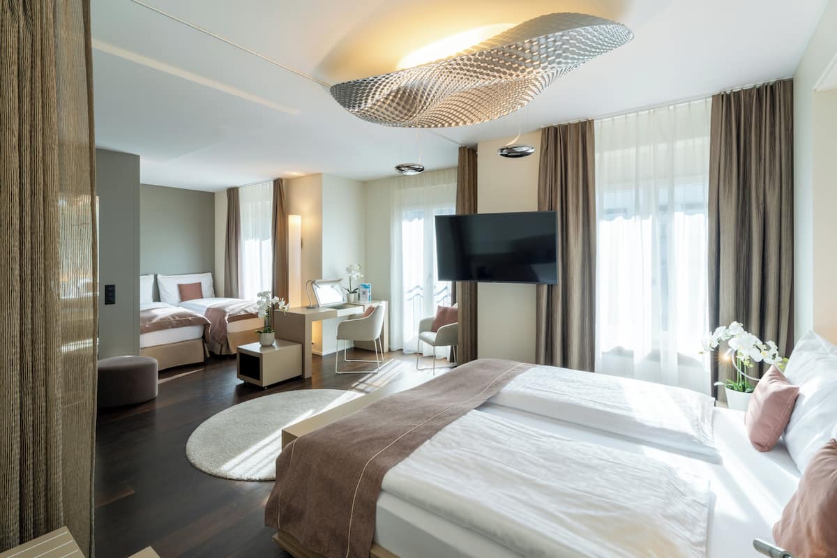 Quarto de hotel moderno com uma cama grande, uma escrivaninha, uma cadeira e uma televisão.