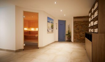 Um saguão de hotel com sauna, balcão de recepção e suporte de toalhas fixado na parede.
