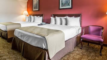 Quarto de hotel com duas camas, uma cadeira e um abajur.