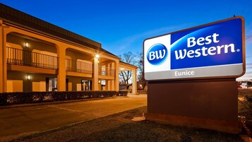 Um hotel Best Western Eunice com um grande letreiro iluminado, uma área externa coberta com corrimãos e uma fachada de edifício bem iluminada.