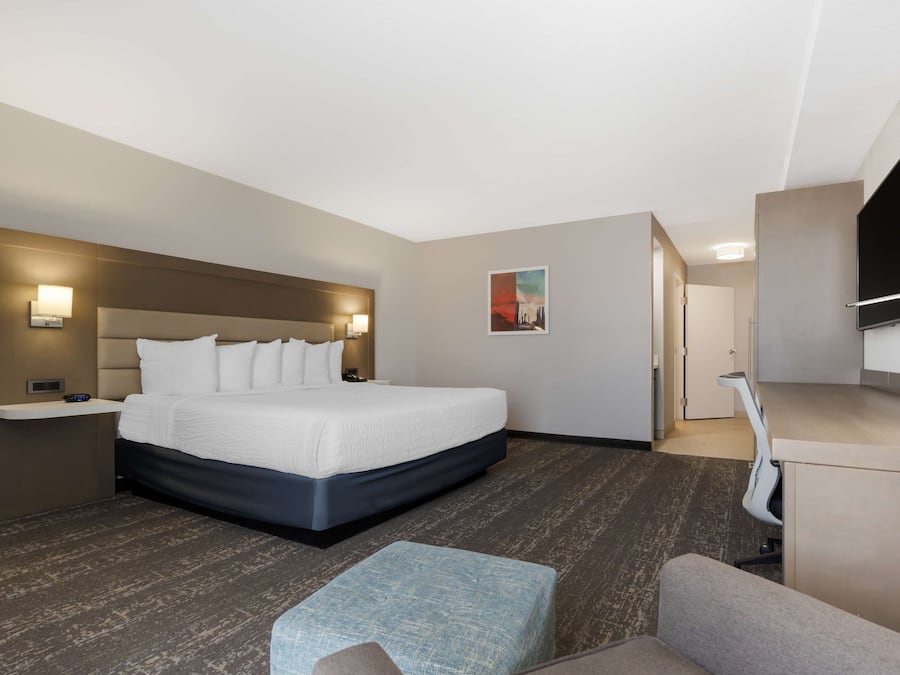Quarto de hotel moderno com uma cama grande, mesas de cabeceira, escrivaninha e televisão de tela plana.