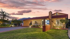 Um edifício com telhado de telhas vermelhas, uma placa com a inscrição "Best Western" e um gramado bem cuidado.