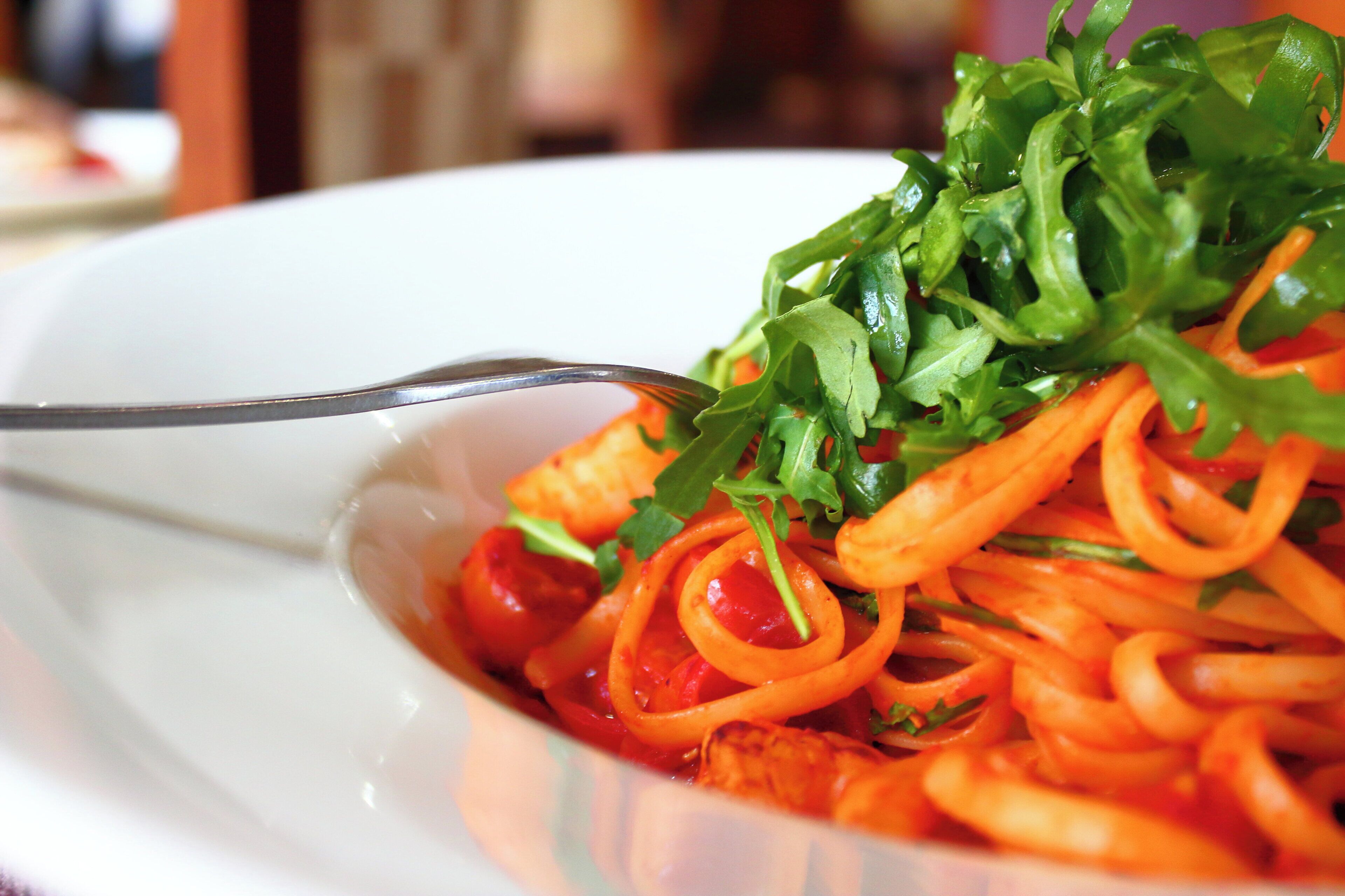 Prato branco com salada de cenoura e folhas verdes, um garfo ao lado.