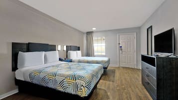 Quarto de hotel com duas camas, cómoda, televisão e janela com cortinas.