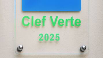 Um sinal com um símbolo de chave e o texto 'Clef Verte 2025' fixado em uma parede.