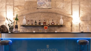 Uma área de bar com parede de pedra, balcão azul e dois bancos.