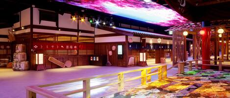 Um edifício japonês tradicional com pisos de esteira de tatame, vigas de madeira e um painel digital no teto.