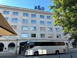 Um ônibus branco estacionado em frente a um edifício com um grande letreiro 'a&o'.