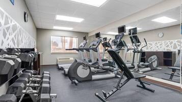 Uma academia com diversos equipamentos de exercício, incluindo esteiras, elípticos e pesos livres.