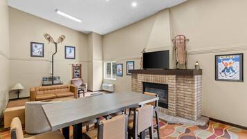 Quarto com lareira, televisão e área de jantar com cadeiras e mesa.