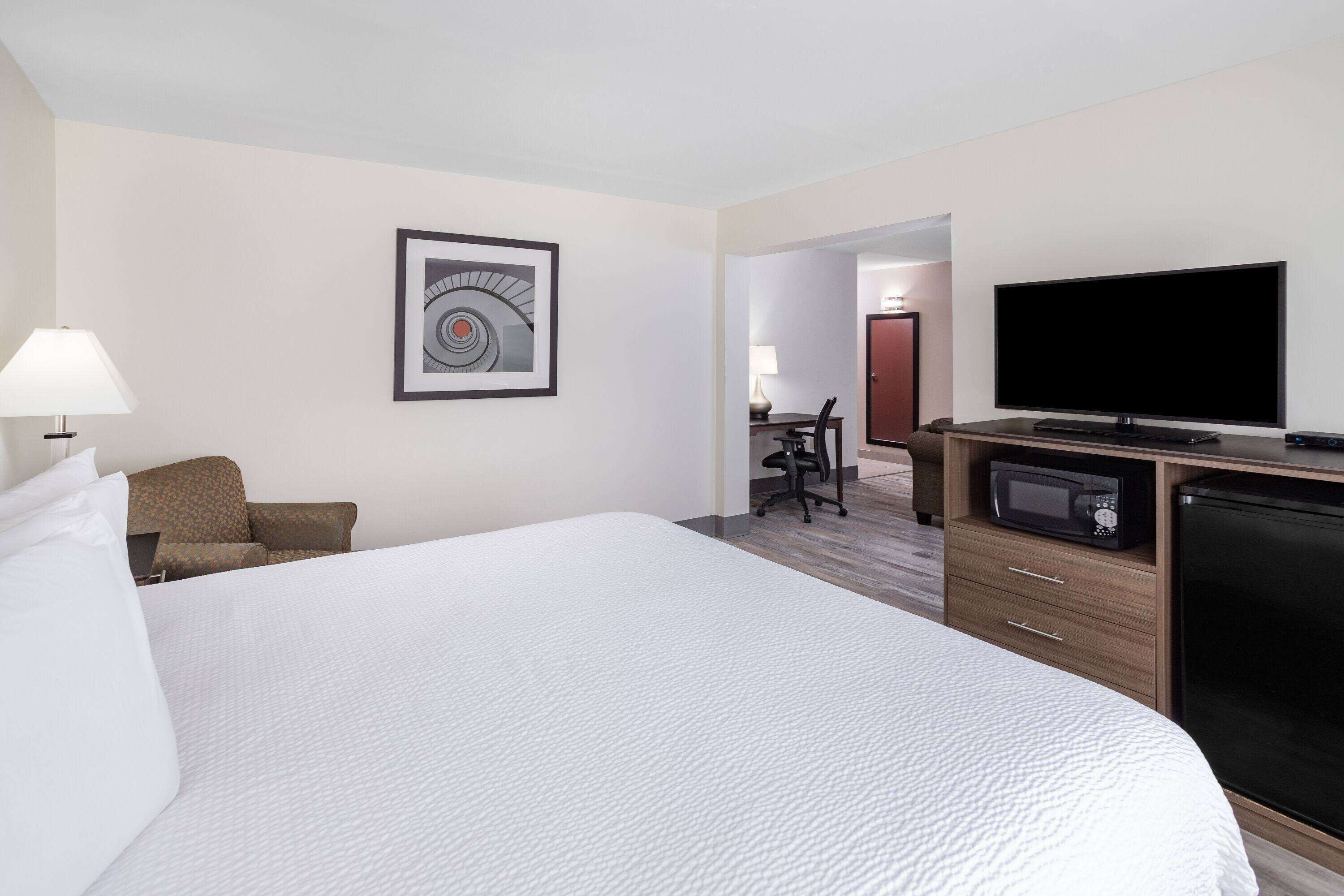 Quarto de hotel com cama grande, televisão de tela plana, micro-ondas e escrivaninha com cadeira.