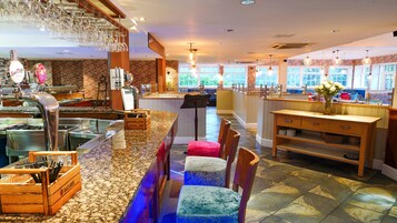 Uma área de bar com bancada de granito, banquetas e suporte para copos de vinho.