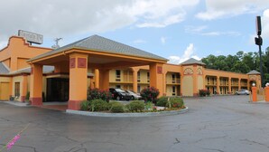 Um hotel com fachada amarela, várias varandas e uma área de entrada coberta.