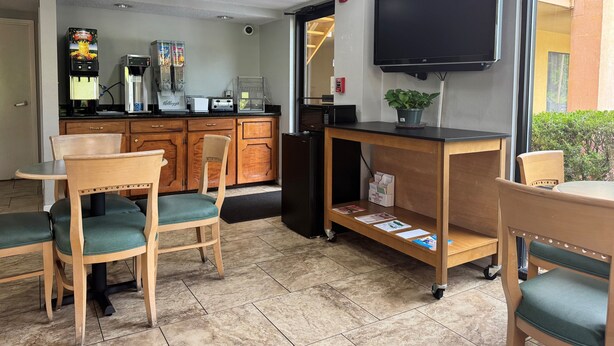 Um saguão de hotel com uma máquina de café, uma televisão e mobiliário de madeira.