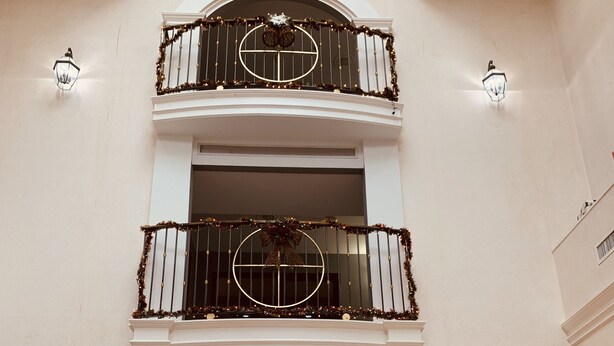 Um hall imponente com teto alto, escadaria central e portas duplas no final.