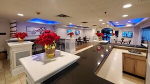 Um hall de hotel moderno com uma ilha central, áreas de estar e um bar.
