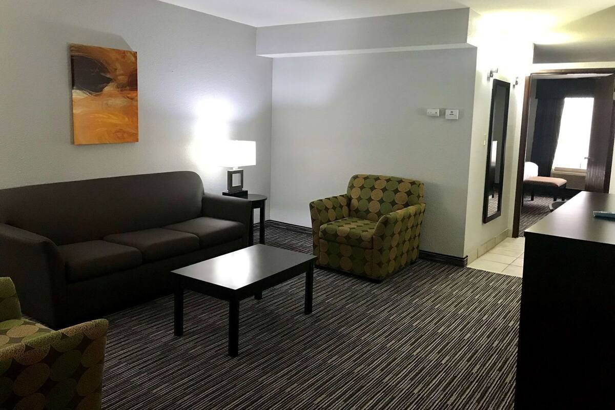 Uma sala de estar com sofá, poltrona, mesa de centro e um quadro na parede.