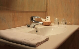 Uma casa de banho com uma pia branca, um espelho e uma toalha.
