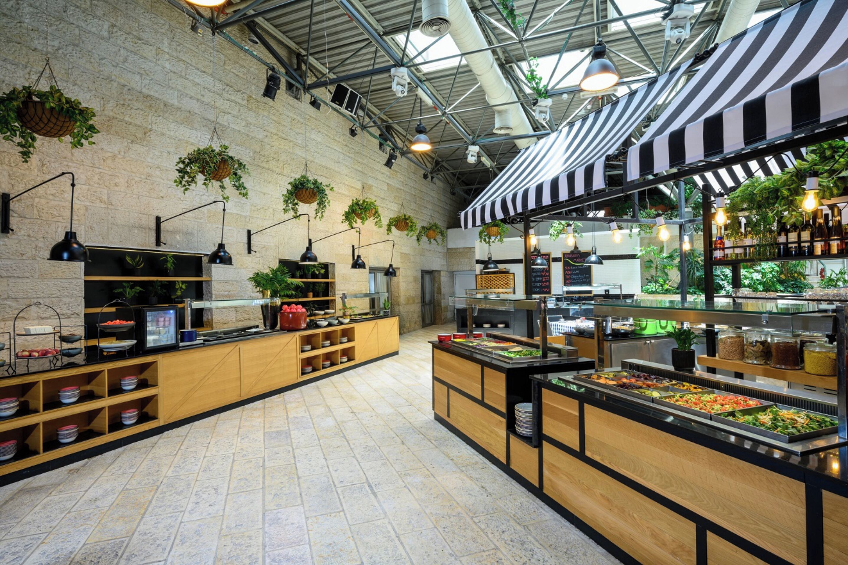 Uma área de buffet com vários pontos de alimentação, plantas pendentes e um toldo listrado.