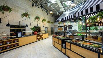 Uma área de buffet com vários pontos de alimentação, plantas pendentes e um toldo listrado.
