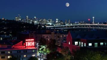 Silhueta urbana noturna com uma ponte destacada, uma lua cheia e um edifício com a placa 'University Inn'.