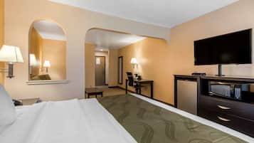 Quarto de hotel com cama, escrivaninha, televisão e micro-ondas.