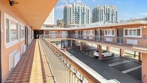 Um hotel com área externa coberta, estacionamento subterrâneo e edifícios altos ao fundo.